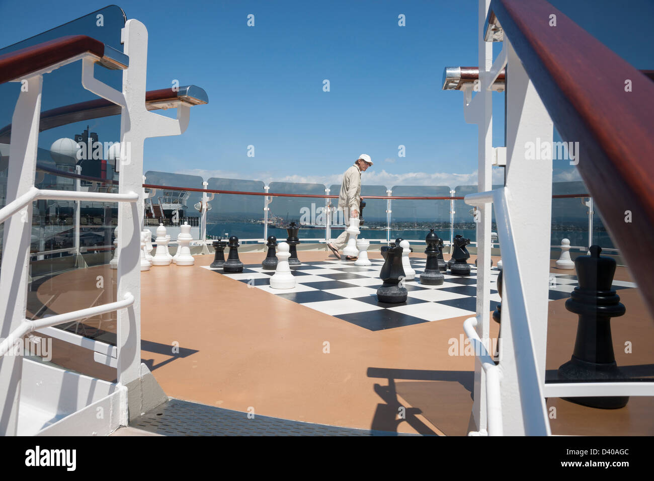 Passenger on cruise ship arranges the chess men on an over-sized chess ...