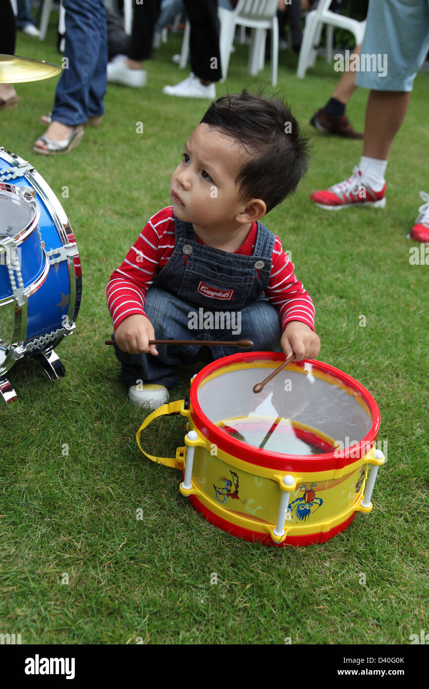 It's a photo of a young child boy who is playing drums on a kid toy ...