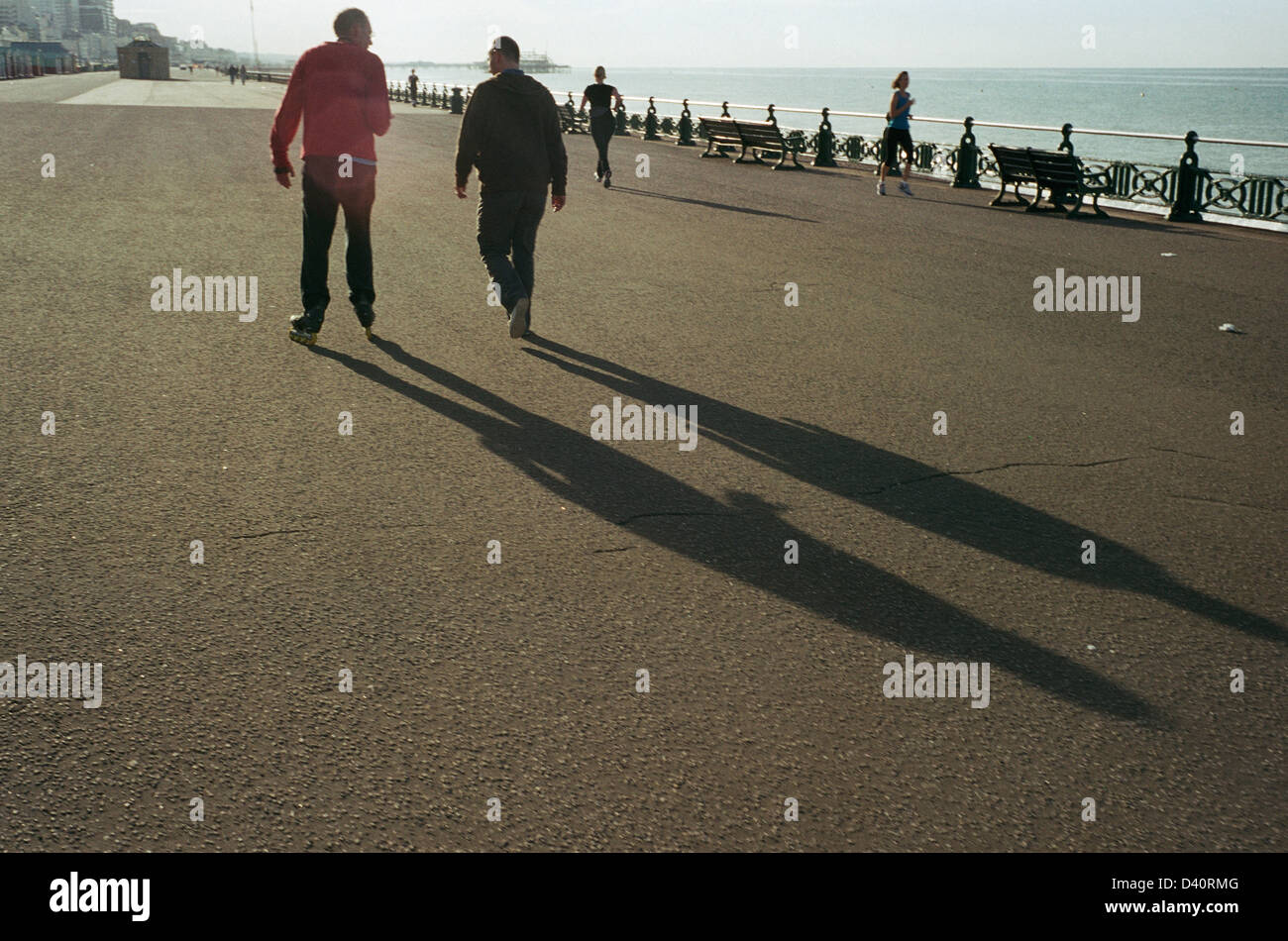 Walking, rollerblading, long shadows, Brighton, UK Stock Photo - Alamy