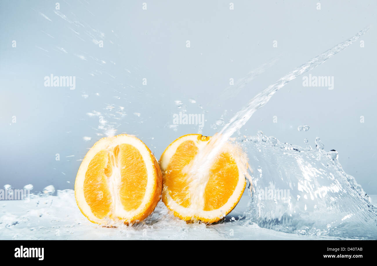Halves of orange thrown water against the light blue background Stock ...