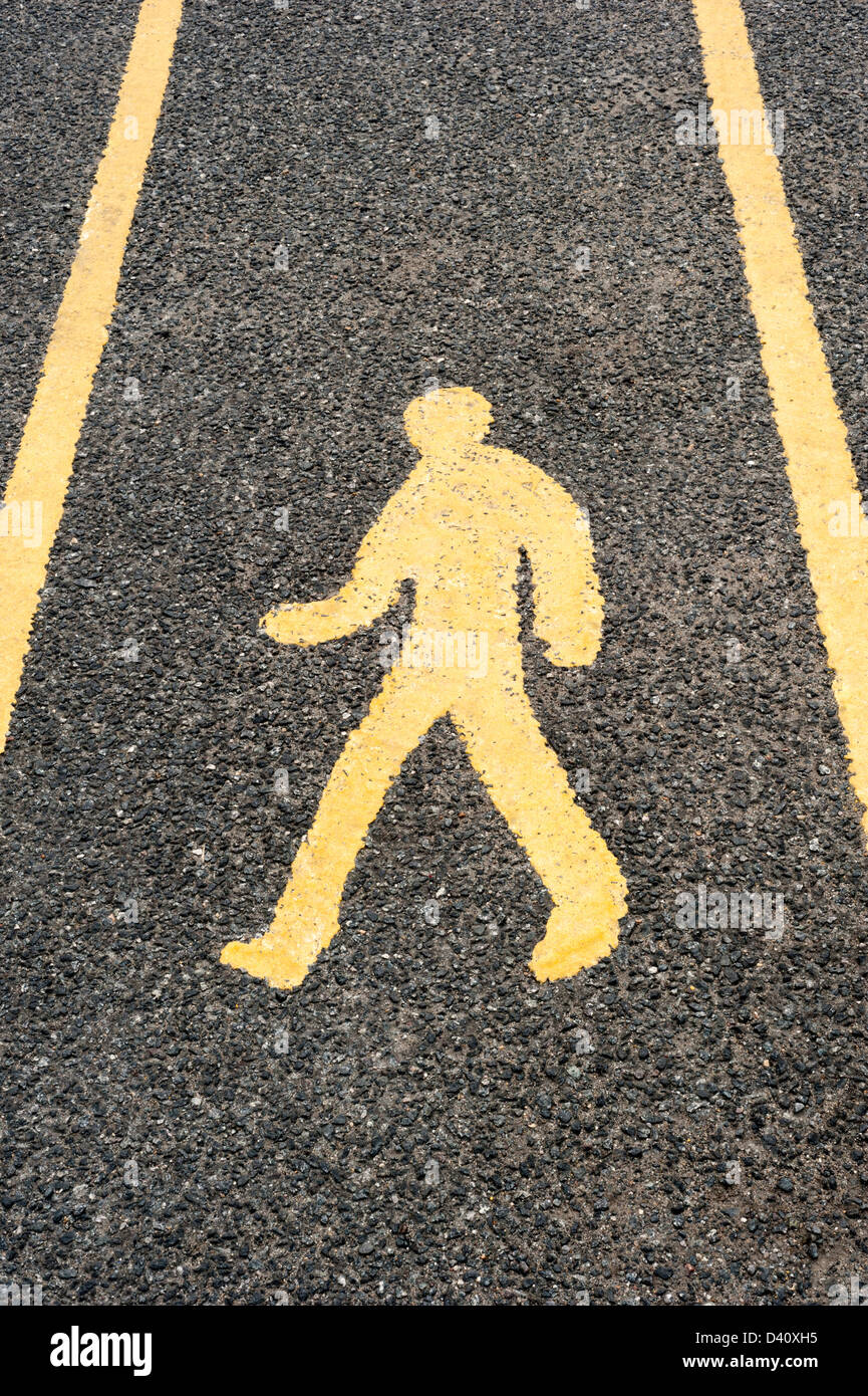 Yellow pedestrian road safety walkway sign painted a road in a car park ...