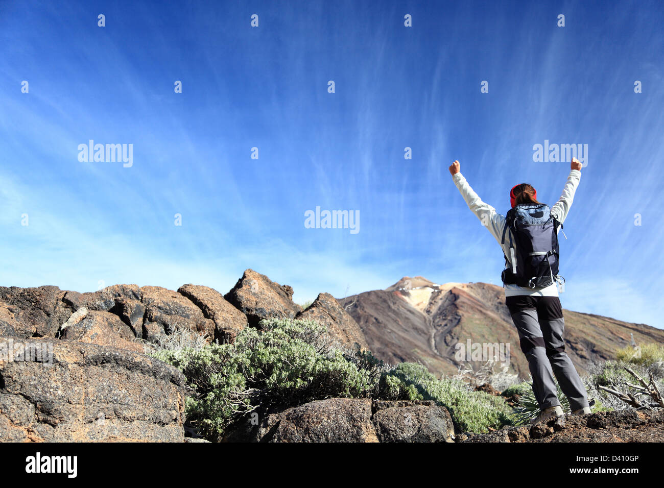 Happy hiking woman with arms raised overcoming challenges on volcano ...