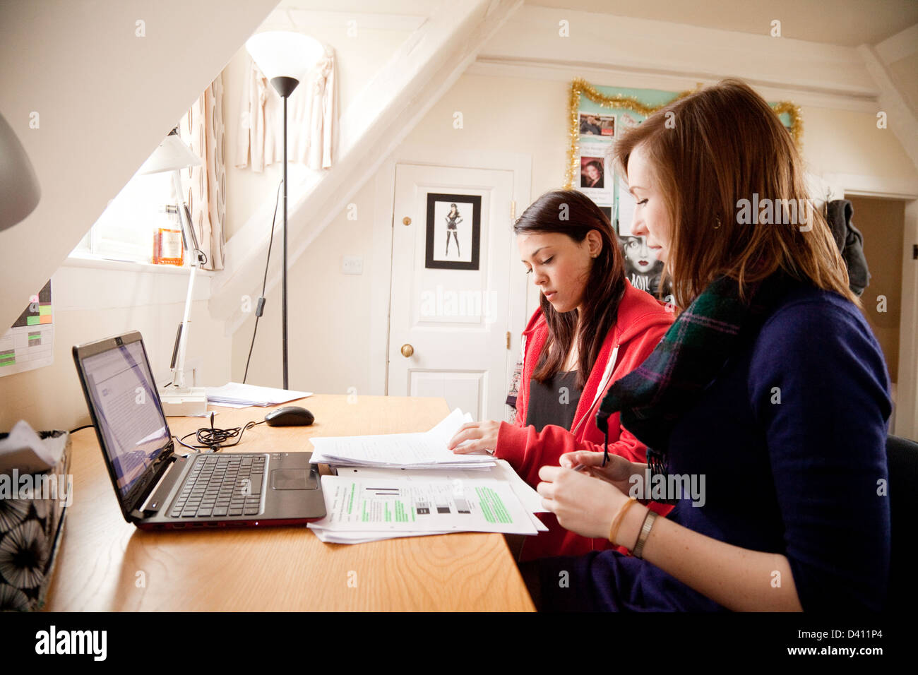 Two women students studying together at their desk with laptop computer ...