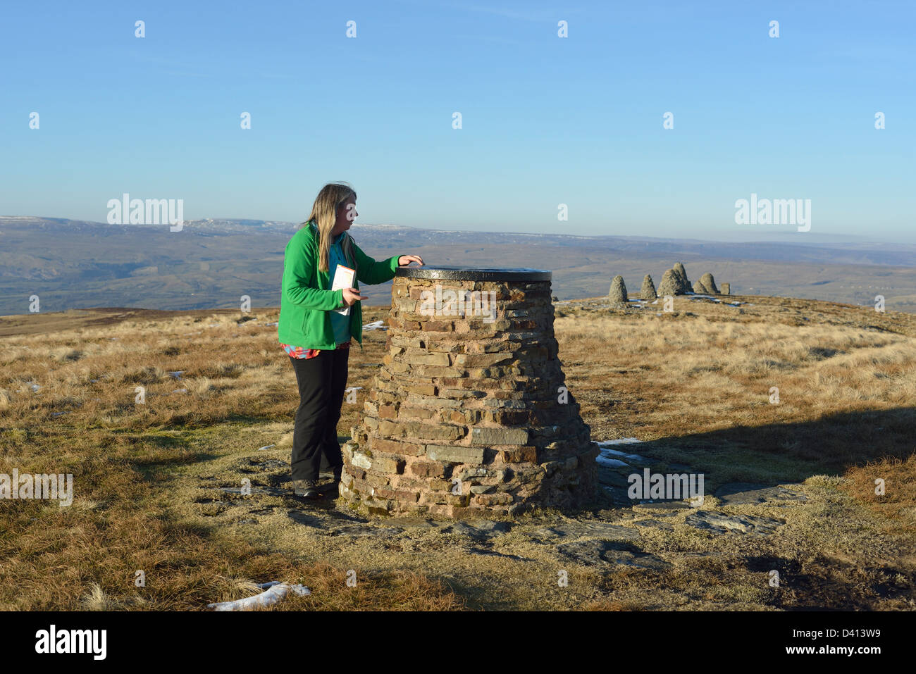 Walker with O.S. map at viewpoint cairn. Hartley Fell, Cumbria, England ...