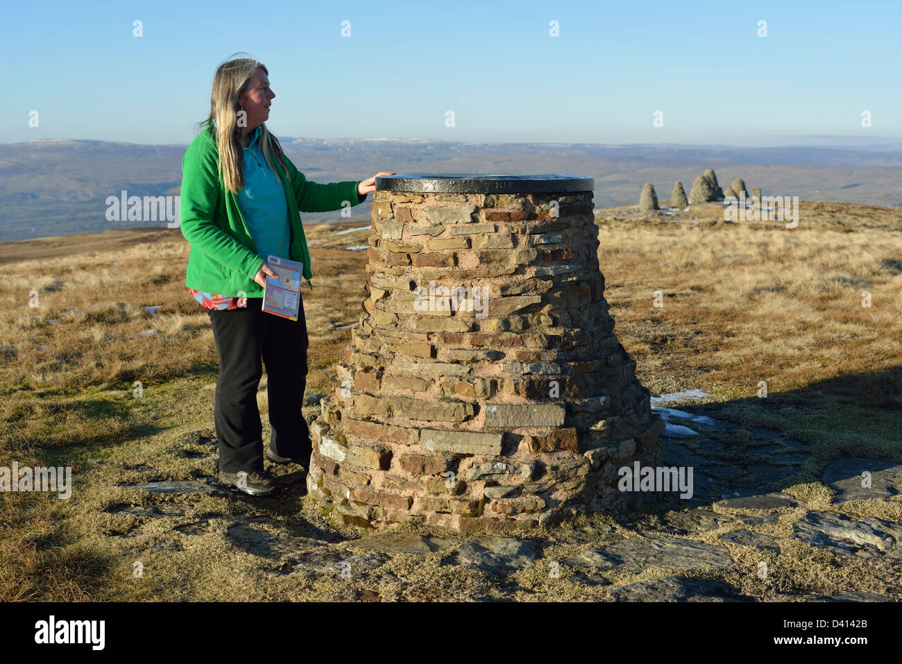 Walker with O.S. map at viewpoint cairn. Hartley Fell, Cumbria, England ...