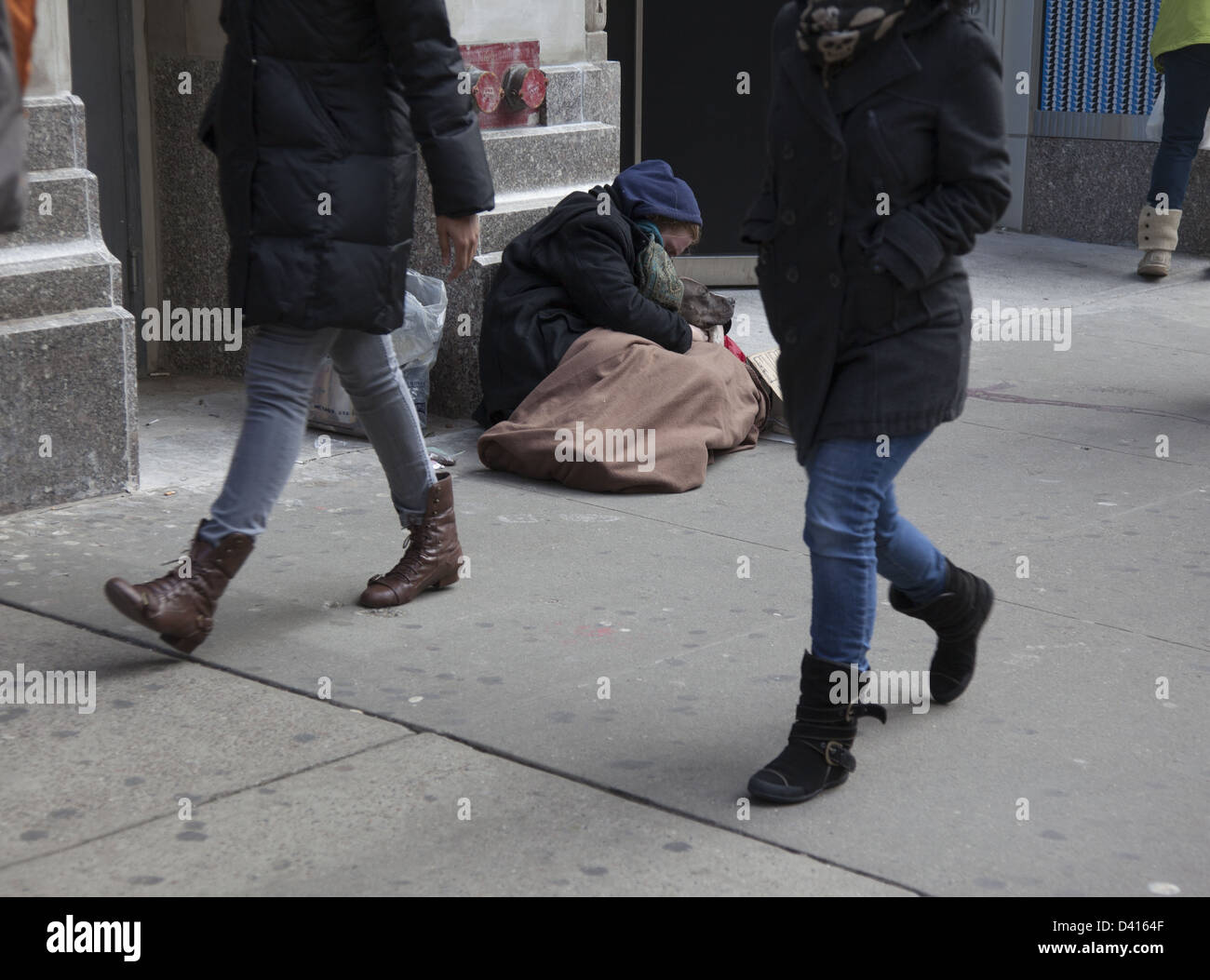 Homeless woman with her dog on the street. Her sign reads, "everyone ...