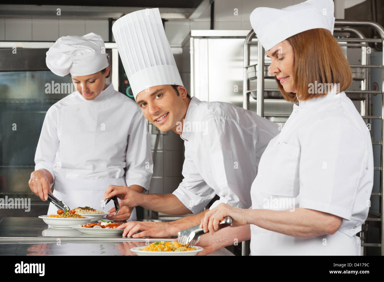 Male Chef With Colleagues Working In Kitchen Stock Photo - Alamy