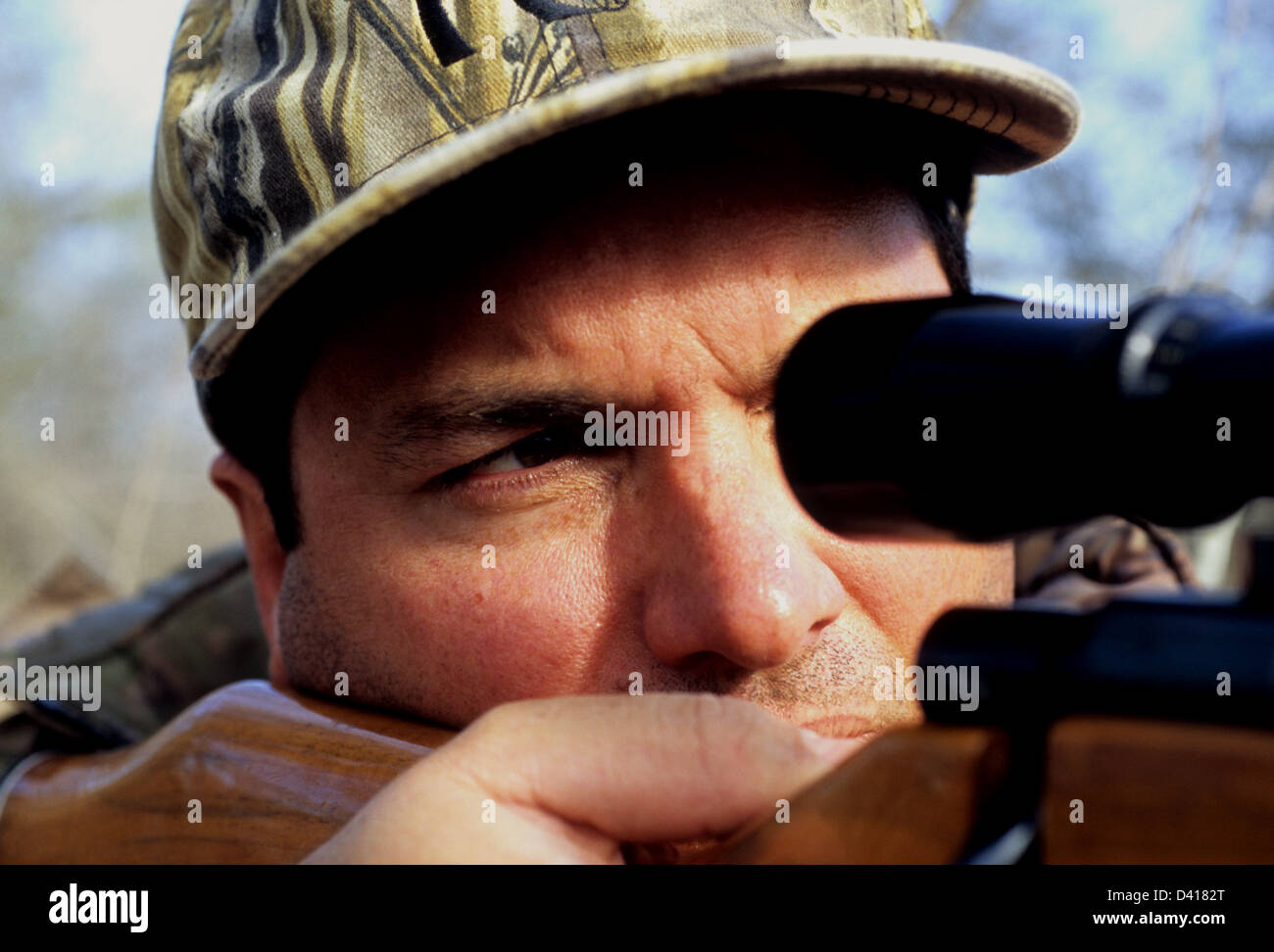 A South Texas deer hunter looking through his scope and aiming a rifle ...