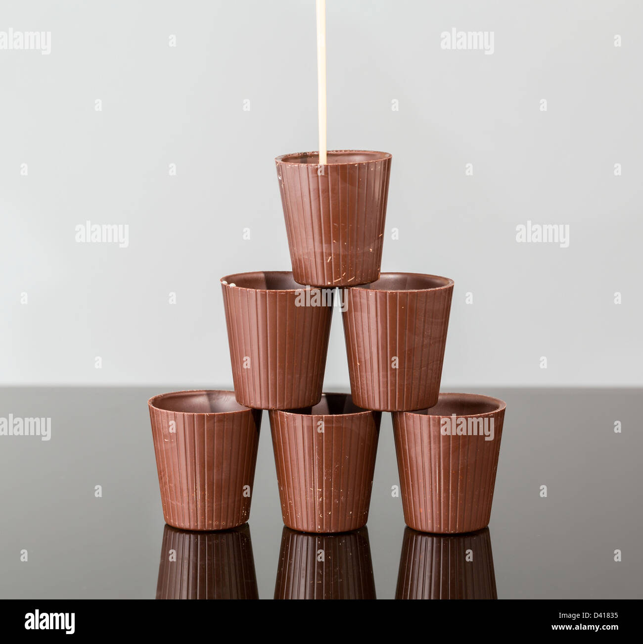 Stack of chocolate shot glasses in pyramid with irish cream poured into ...