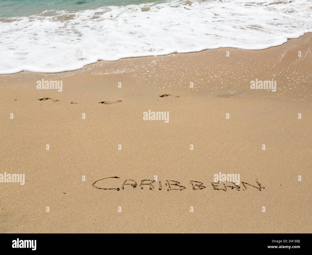 Caribbean words written into sand on beach by sea in St Thomas Stock ...