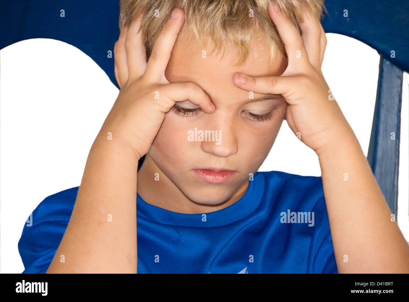 Little boy sitting in a chair pouting with this hands on his head and ...