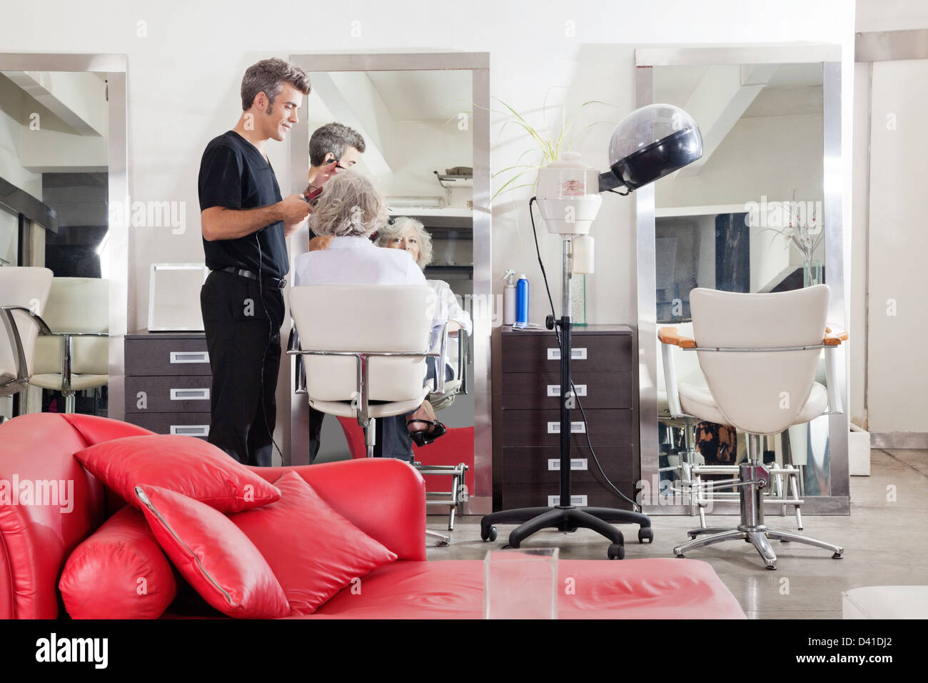 Hairstylist Straightening Client's Hair At Salon Stock Photo - Alamy