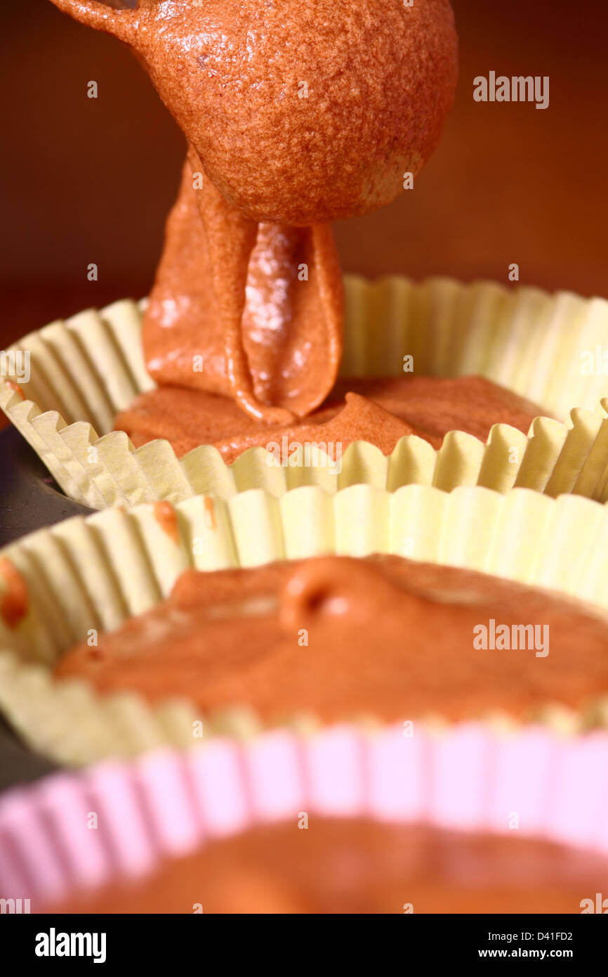Bun cases being filled with chocolate cupcake mixture Stock Photo - Alamy