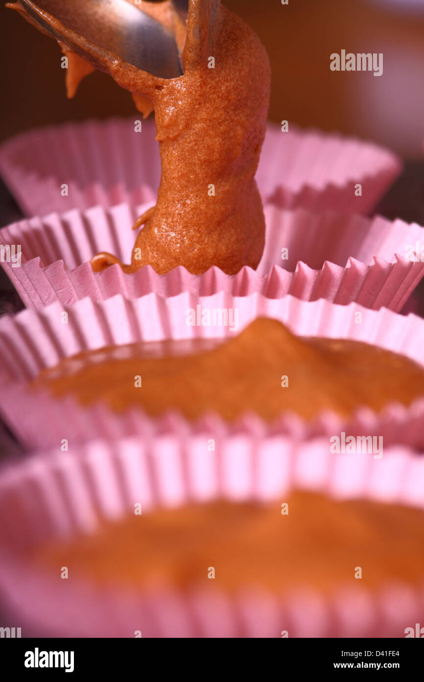 Bun cases being filled with chocolate cupcake mixture Stock Photo - Alamy