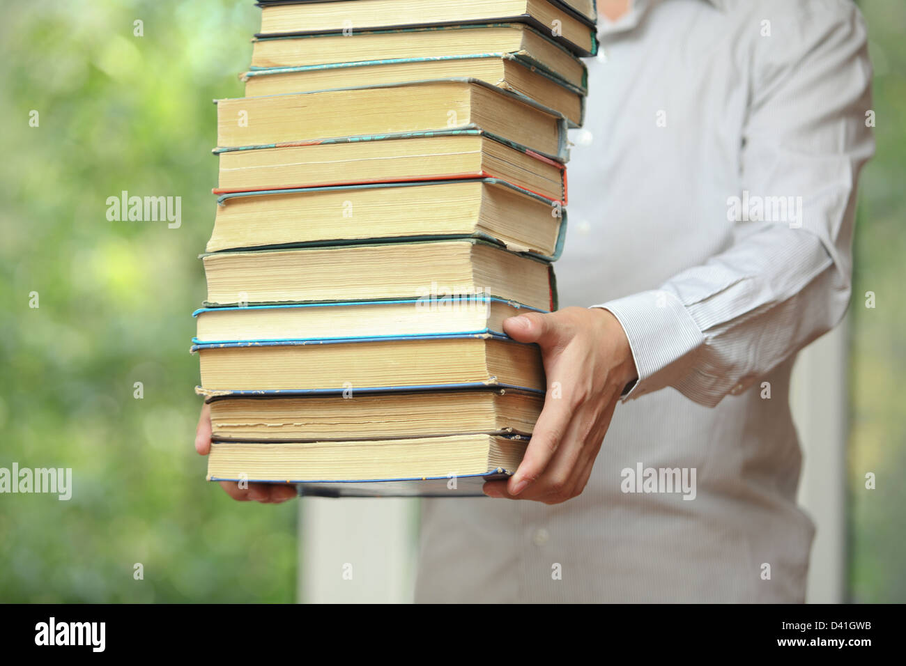 Guy in a shirt holding a stack of old books Stock Photo - Alamy
