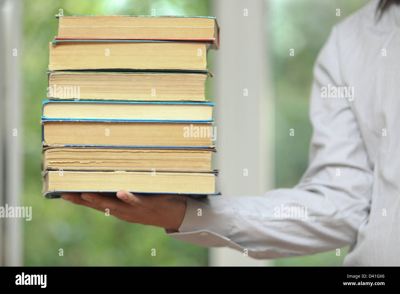 Guy in a shirt holding a stack of old books Stock Photo - Alamy