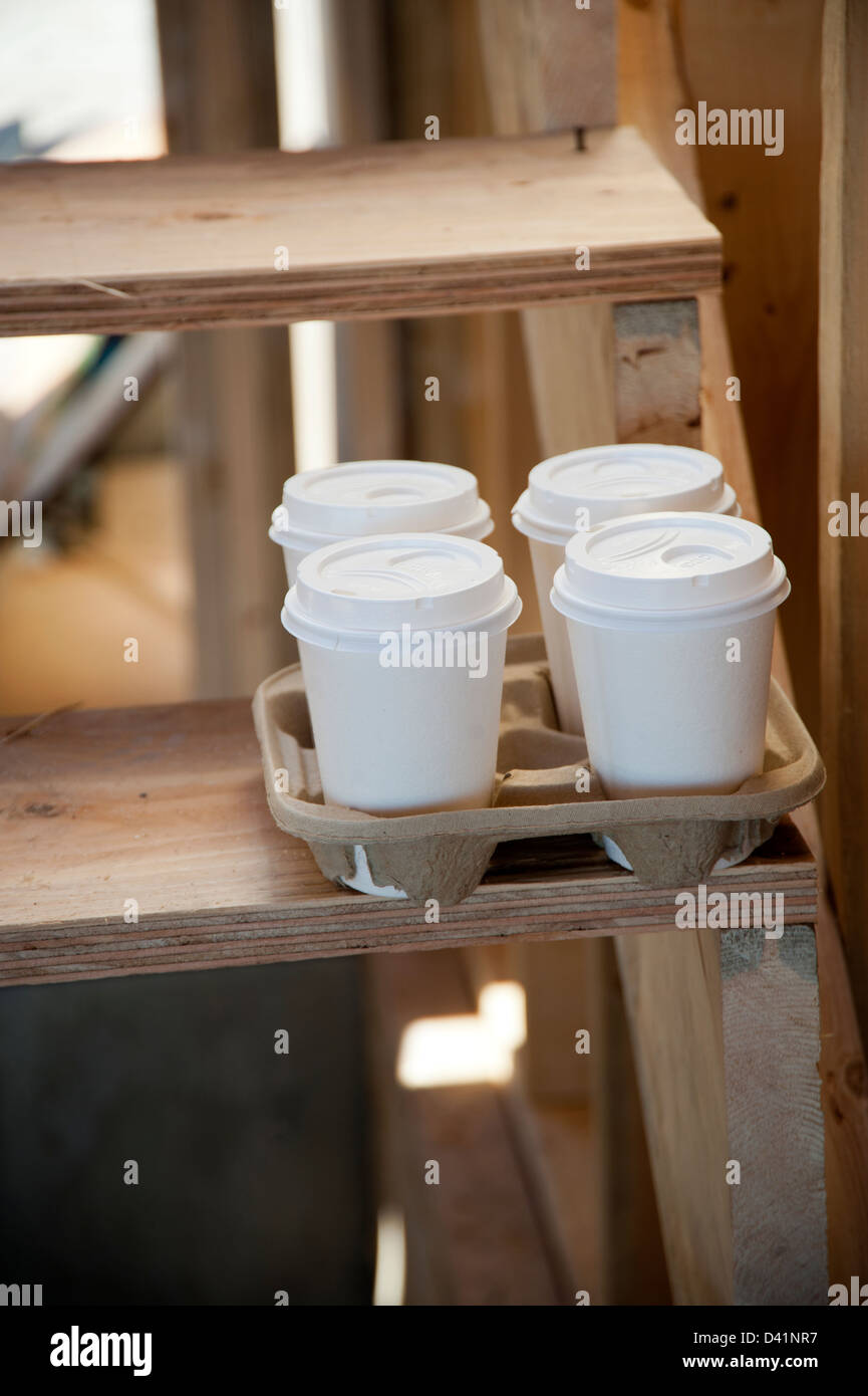 Four styrofoam take away coffee cups sitting on ladder in construction ...