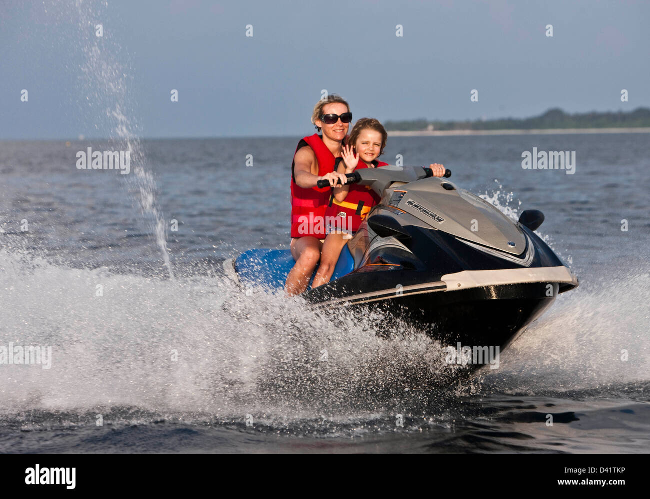 Woman and child on jet ski with water spray, Kuda Hura, Maldives Stock ...