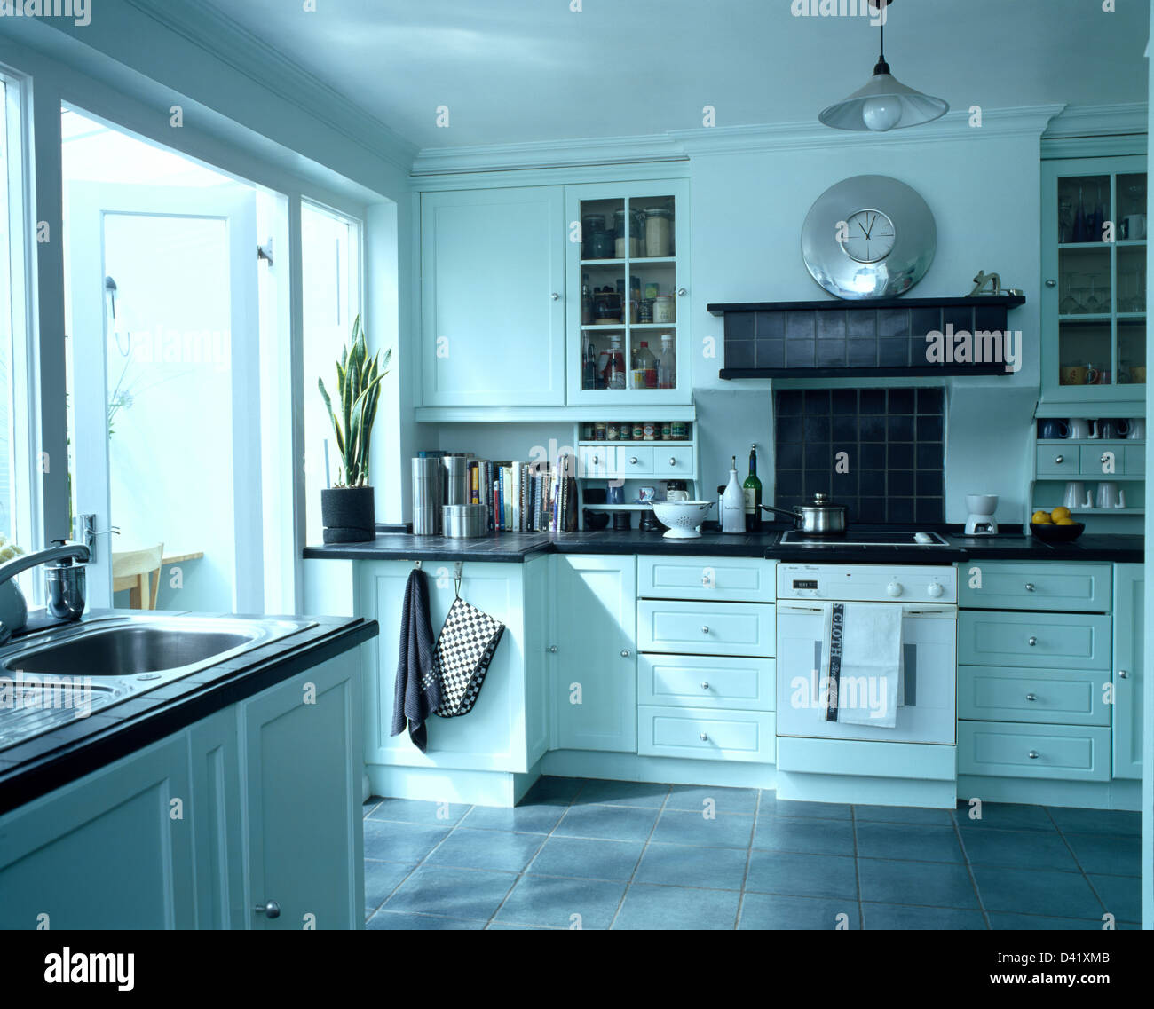 Circular chrome clock above white oven in modern white kitchen Stock ...