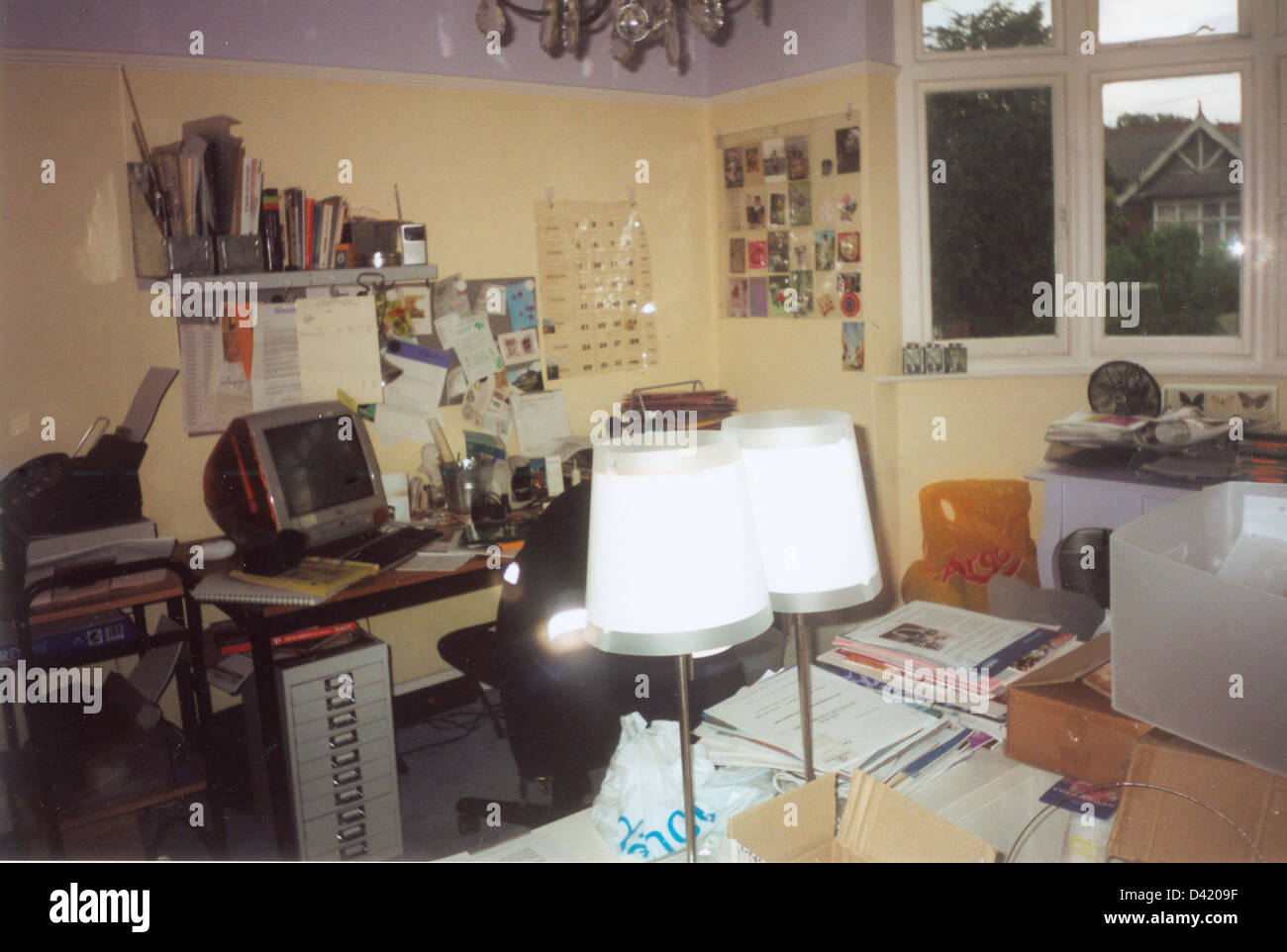 Lighted lamps and old Apple computer on table in untidy study bedroom ...