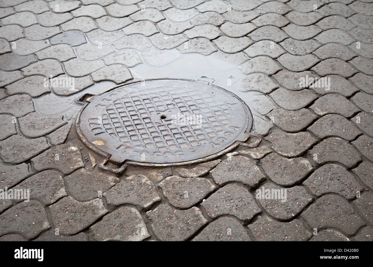 Old round steel sewer manhole on the cobblestone road Stock Photo - Alamy