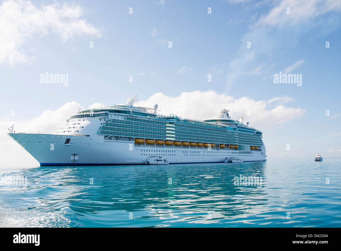 A huge luxury cruise ship anchored under nice skies on calm green water ...