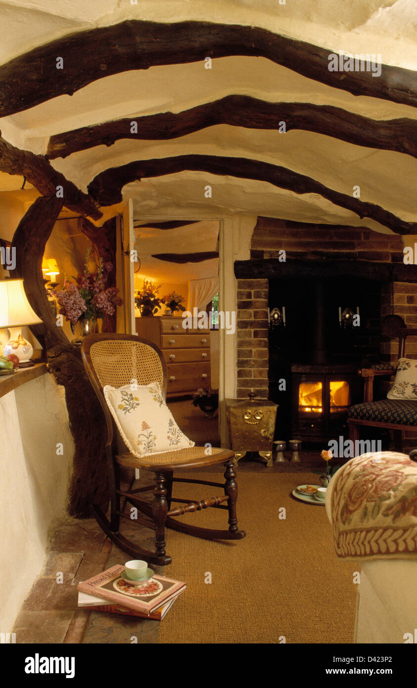 Cane-back rocking chair in small cottage living room with wood-burning ...