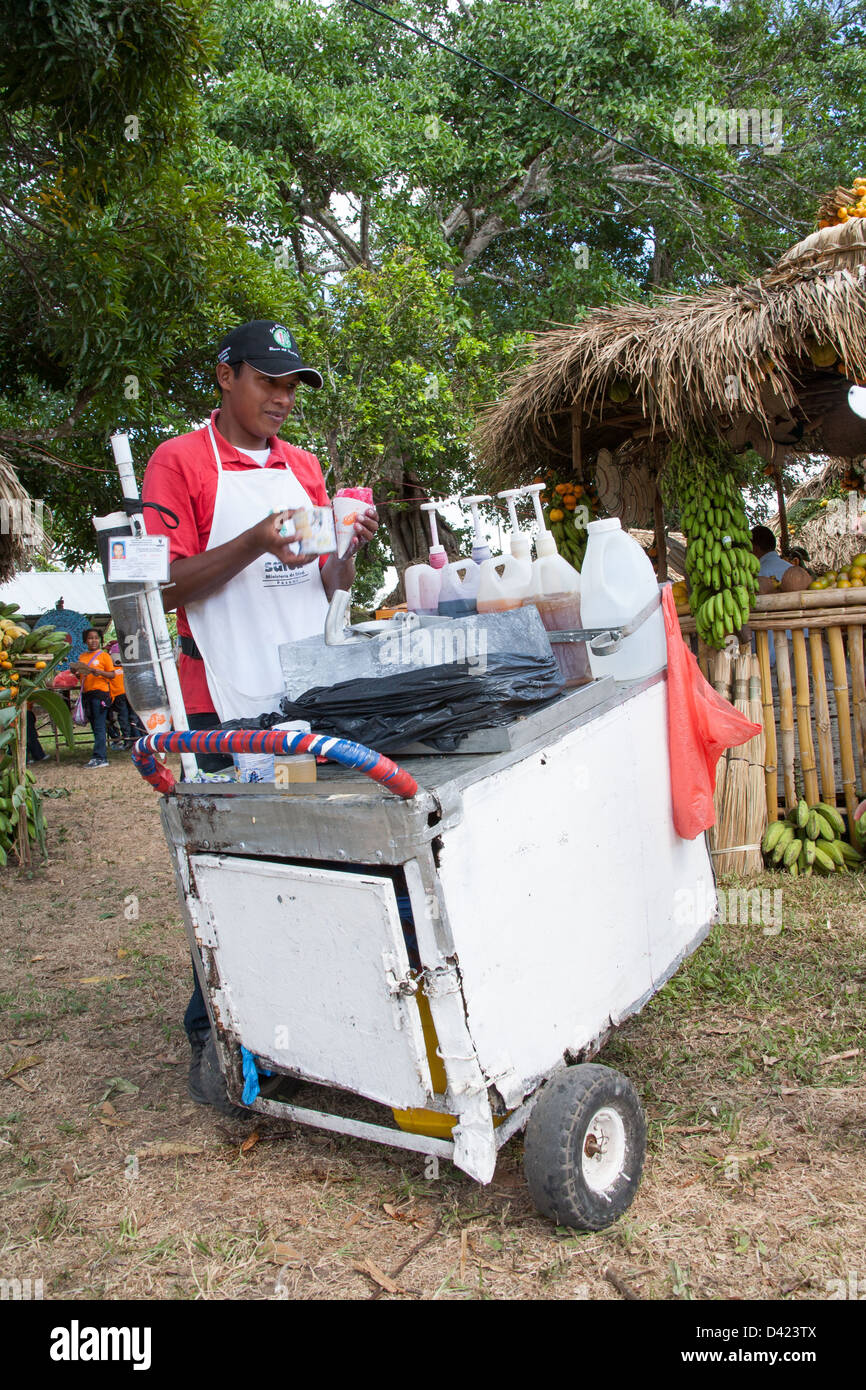 Panamanian man shaving a block of ice with a shaver to make a snow cone ...