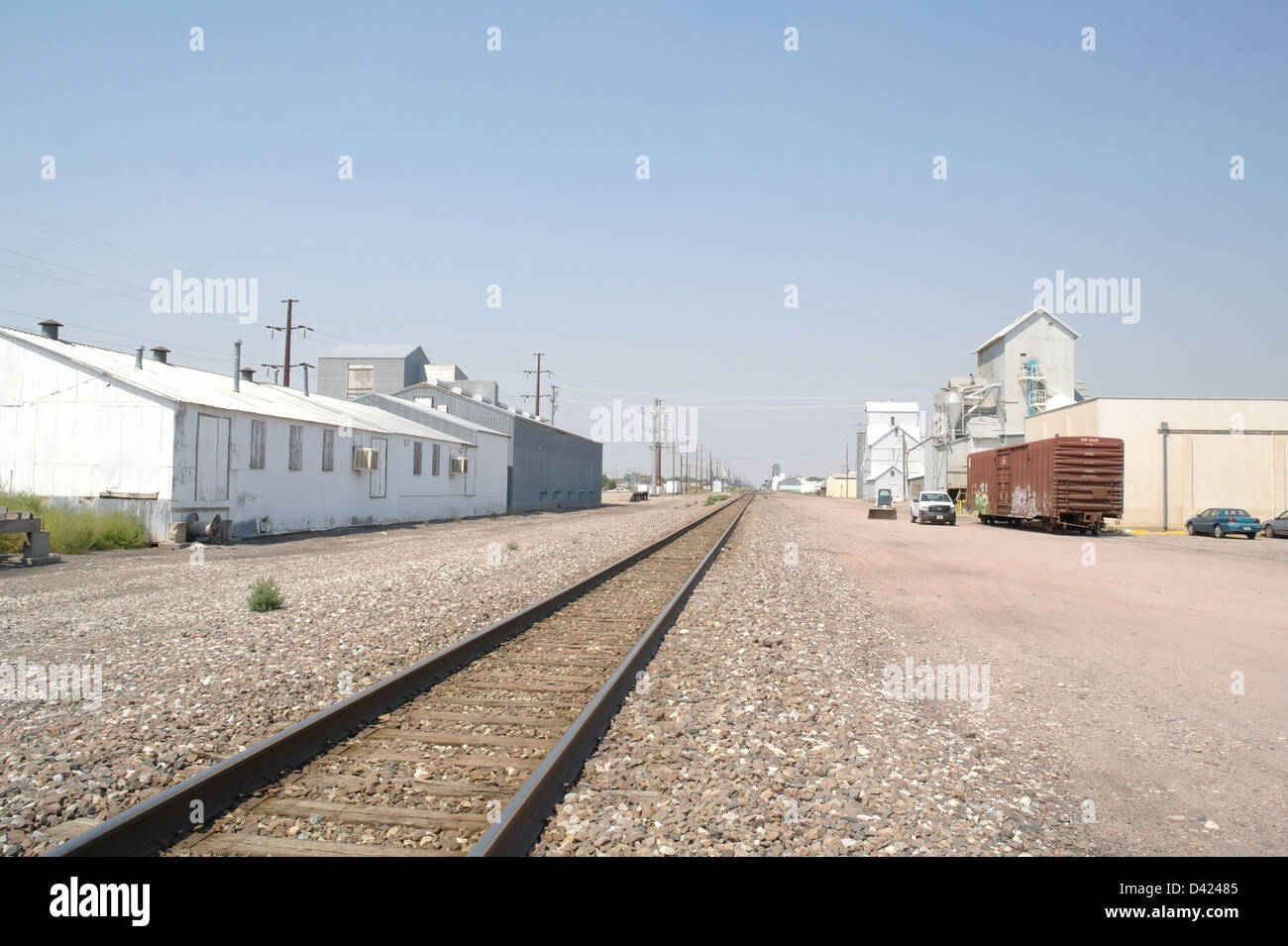 Blue sky view single-track railroad heading west past single-storey ...