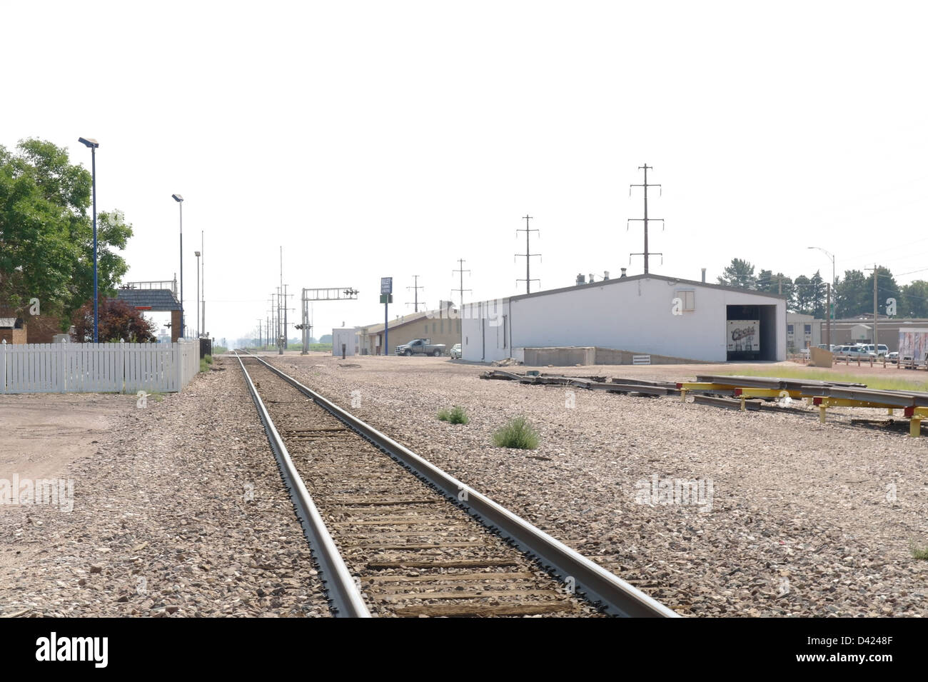 Sunny white sky view single-track railroad heading east past white ...