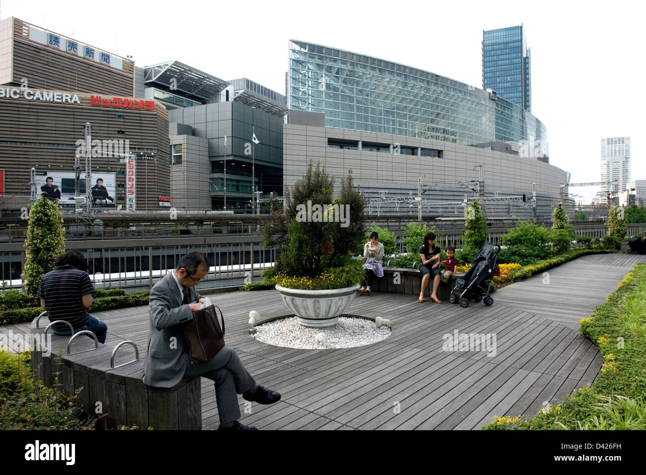 People relaxing on a rooftop garden deck with a view of the Tokyo ...