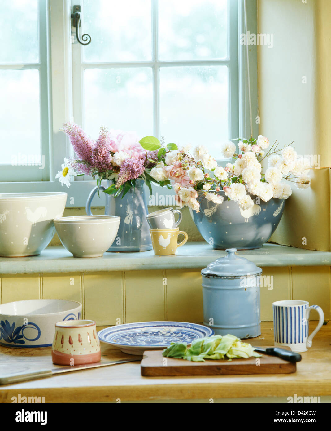 Close-up of white roses and summer flowers in blue pottery jugs on ...