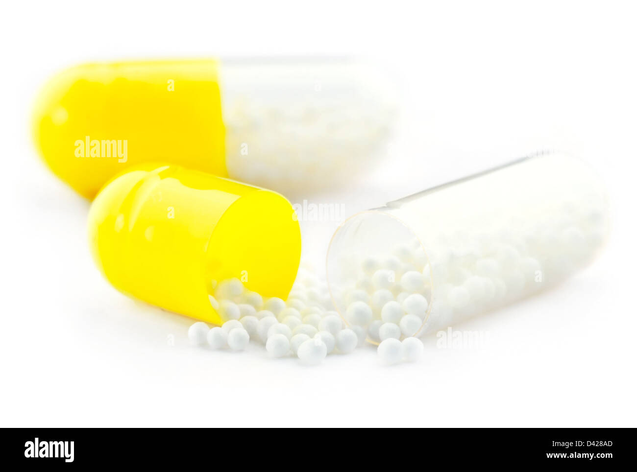Open yellow medicine capsule on white background Stock Photo - Alamy