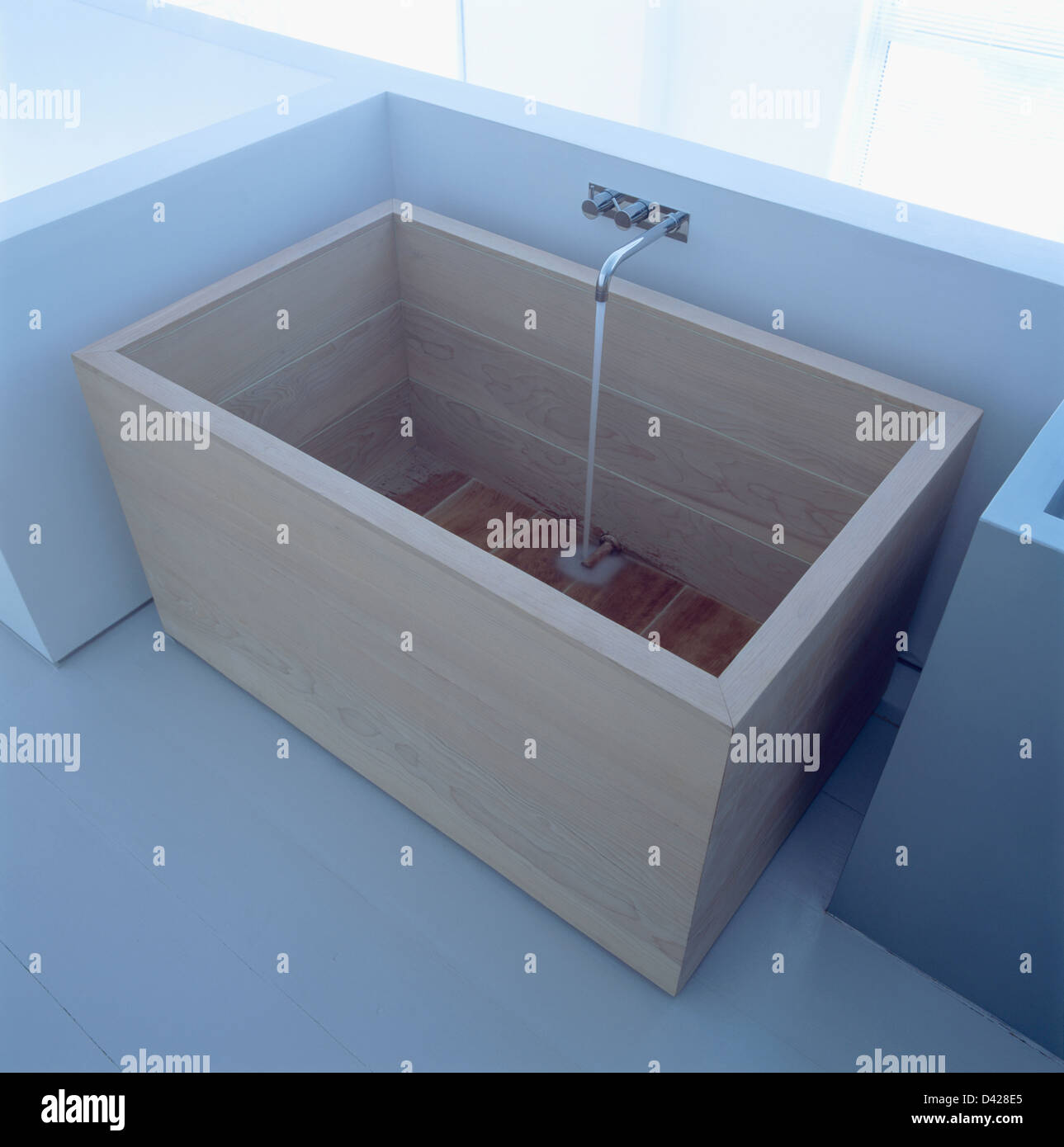 Chrome tap pouring water into rectangular granite bath in city bathroom ...