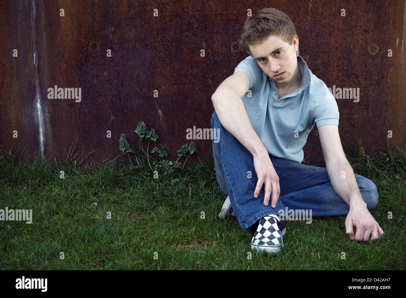 Portrait of young man sitting on ground Stock Photo - Alamy