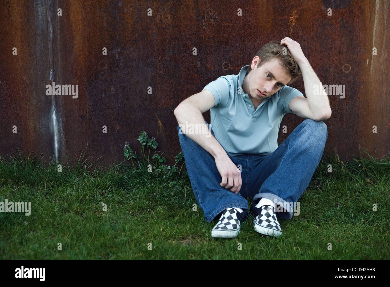 Portrait of young man sitting on ground Stock Photo - Alamy