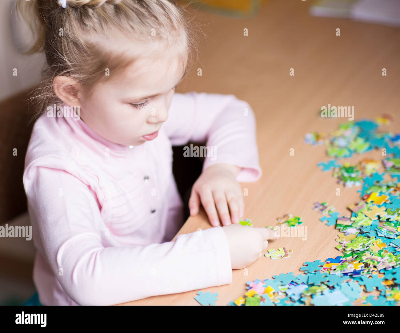 Cute little girl playing puzzles at the table Stock Photo - Alamy
