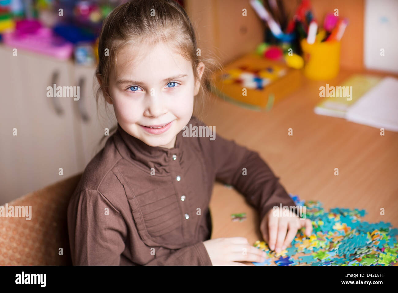 Cute little girl playing puzzles at the table Stock Photo - Alamy