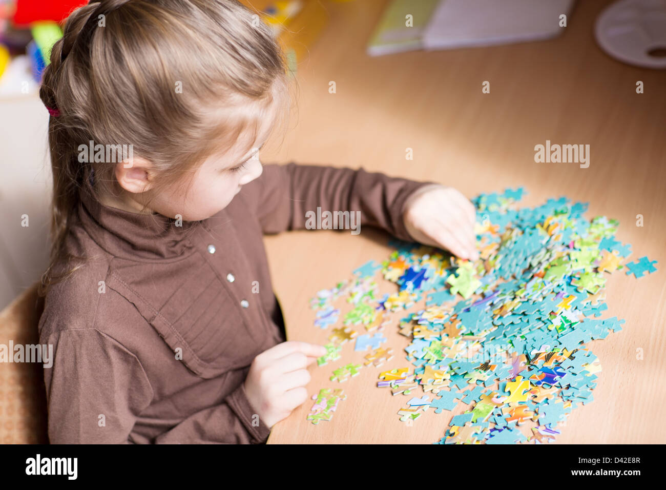 Cute little girl playing puzzles at the table Stock Photo - Alamy