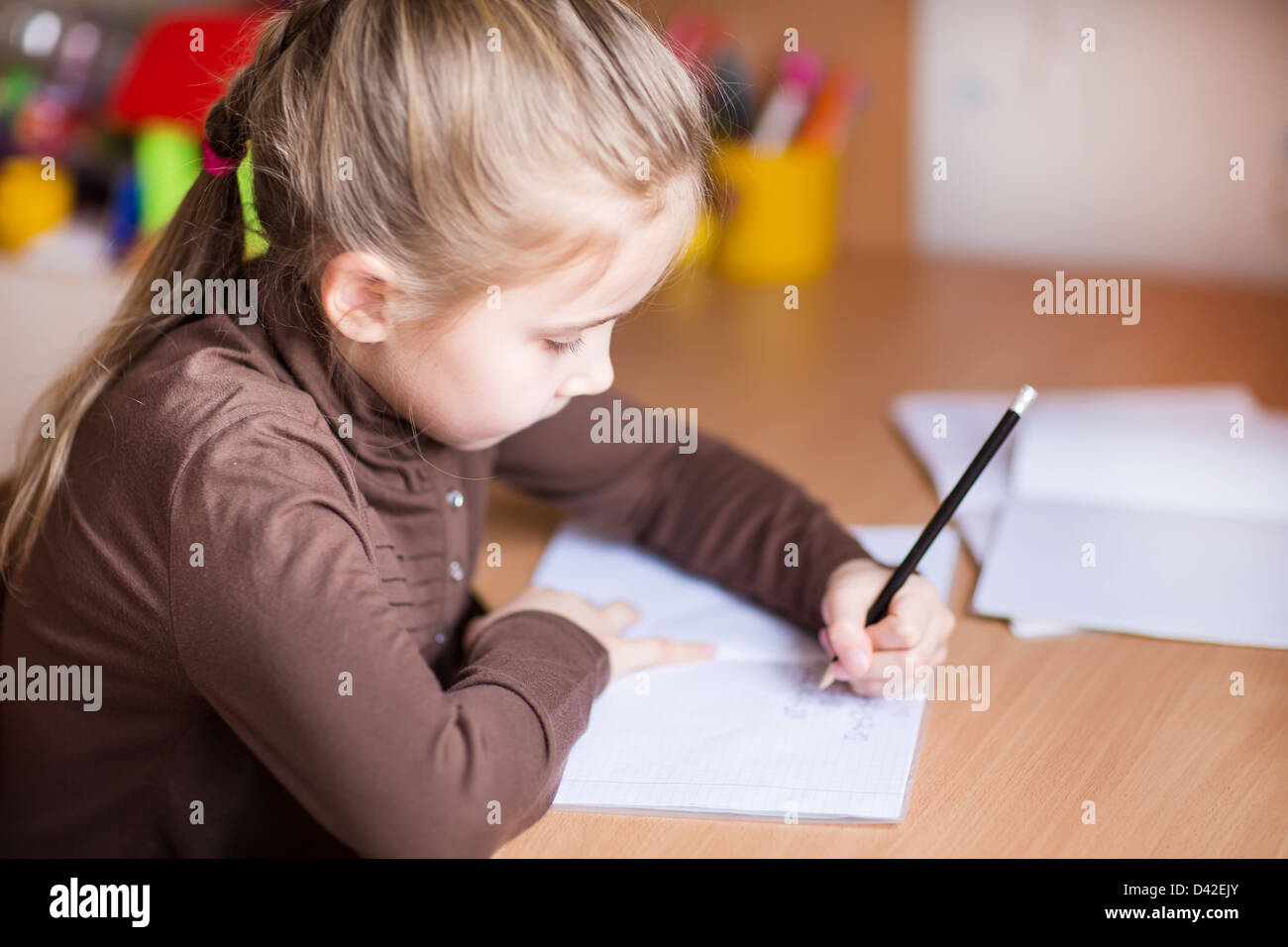 Cute little girl writing her homework at the table Stock Photo - Alamy