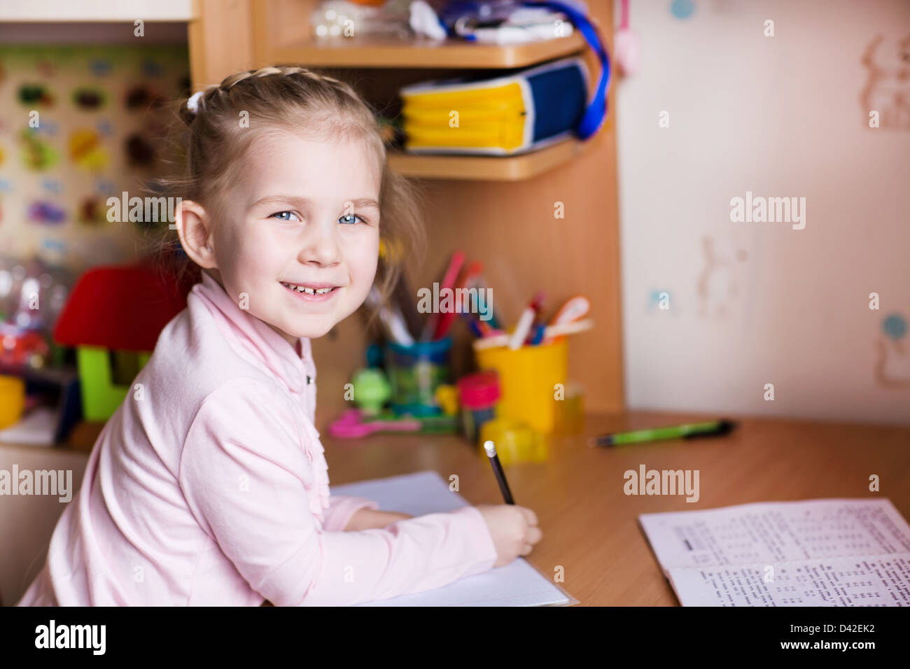 Cute little girl writing her homework at the table Stock Photo - Alamy