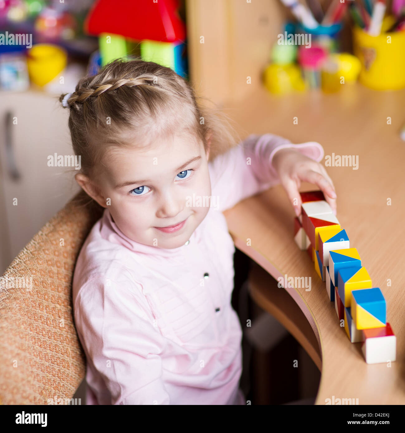 Cute little girl playing with blocks at the table Stock Photo - Alamy