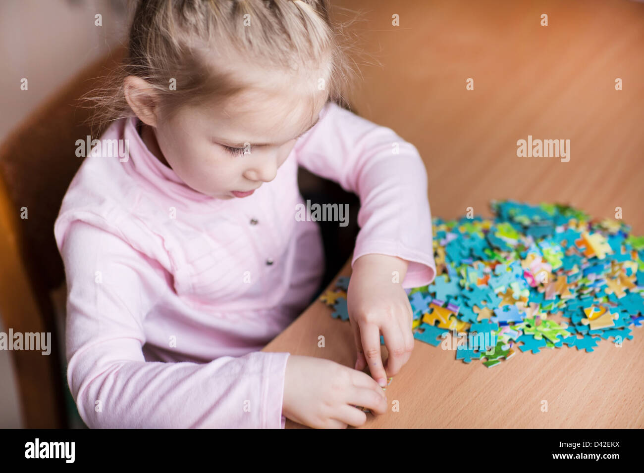 Cute little girl playing puzzles at the table Stock Photo - Alamy