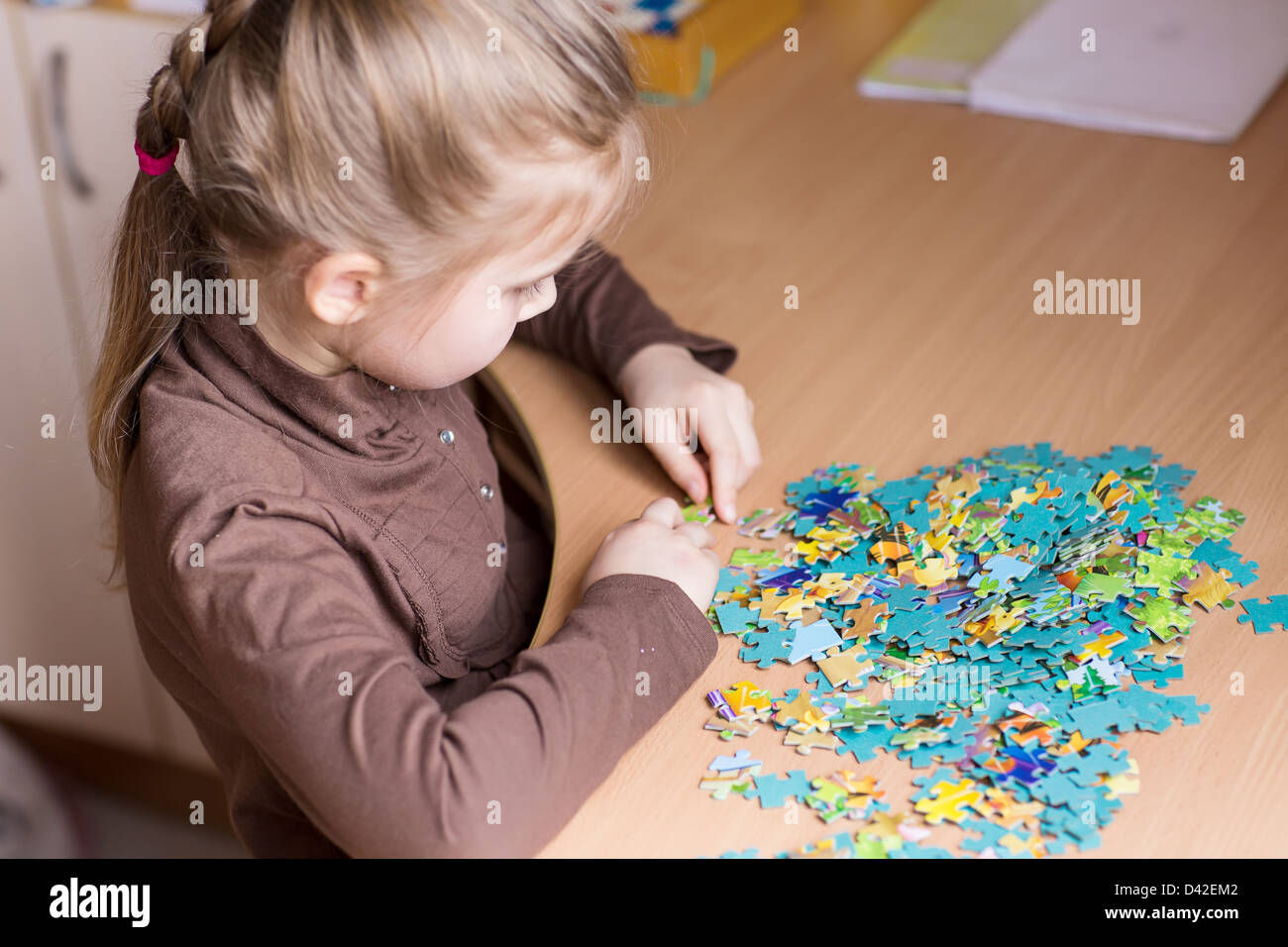 Cute little girl playing puzzles at the table Stock Photo - Alamy
