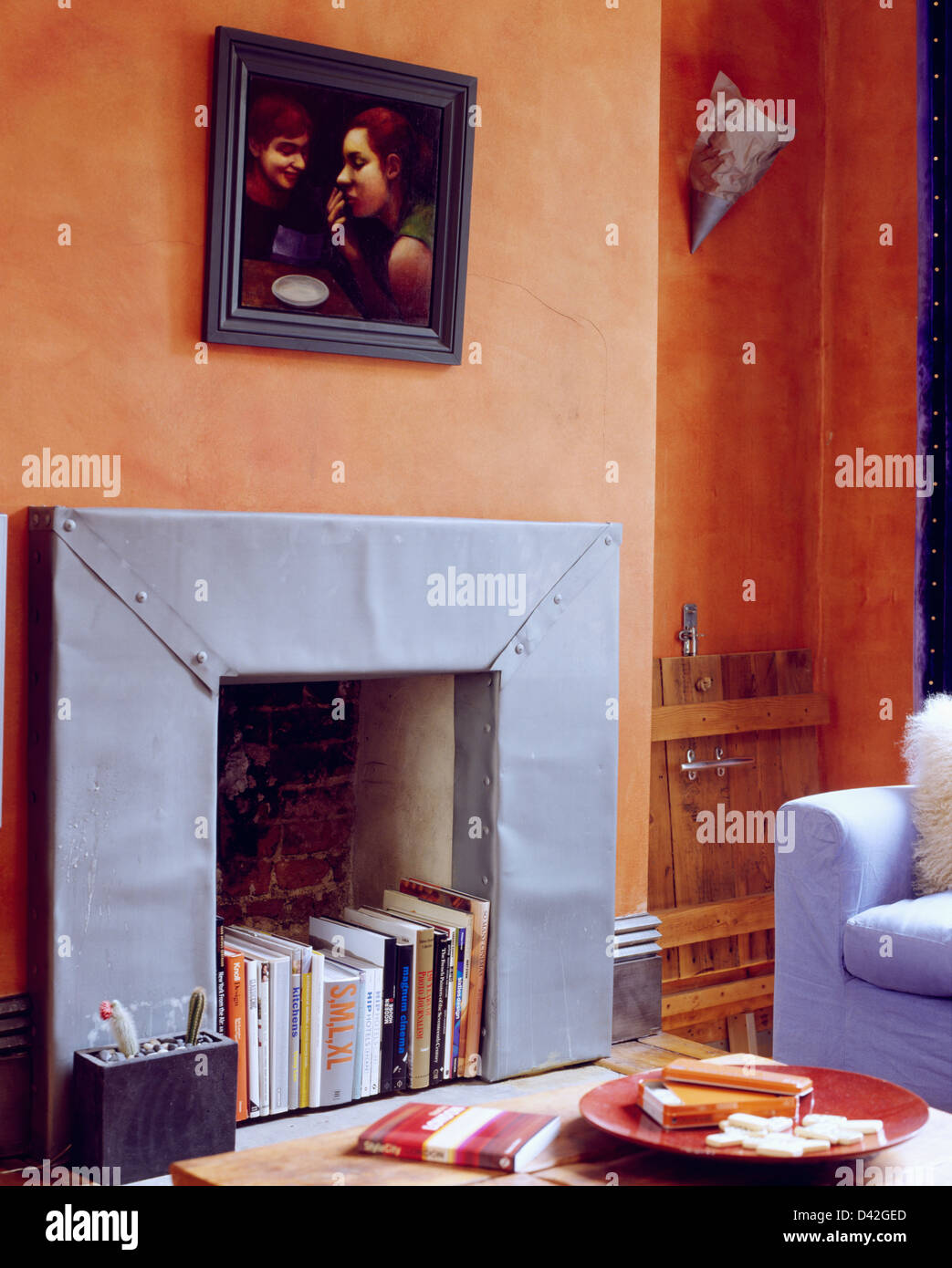 Books stacked in fireplace with home-made metal mantelpiece in ...