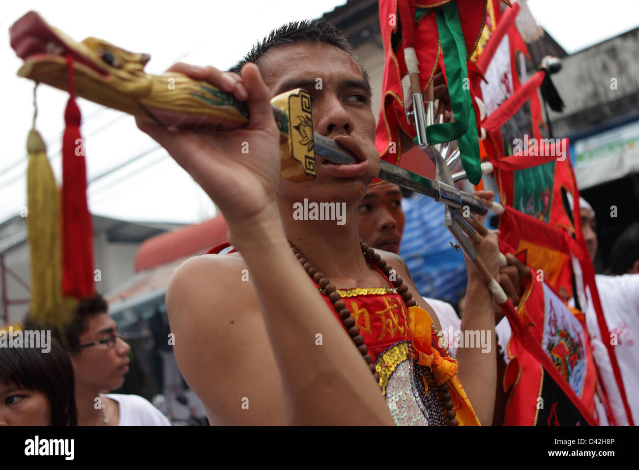 A sword is pierced through the cheeks of a devotee during Phuket ...