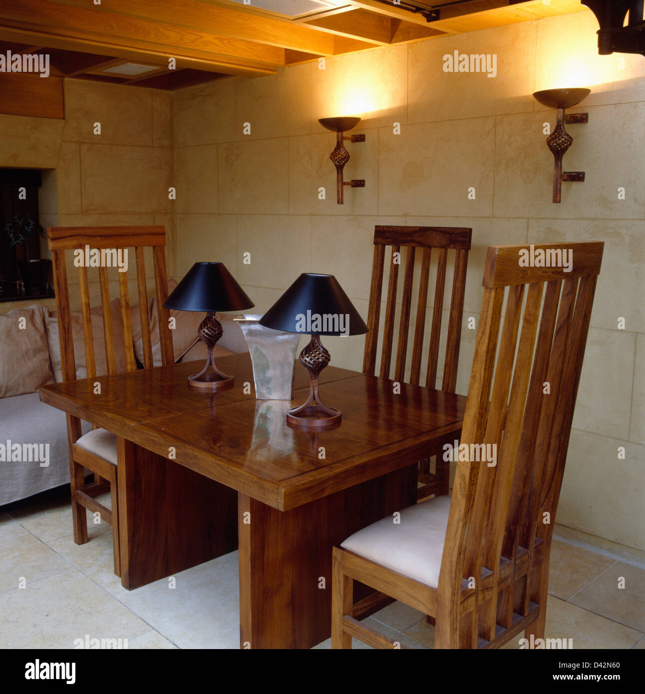 Tall-back wood chairs at table in modern dining room with wall-lights ...