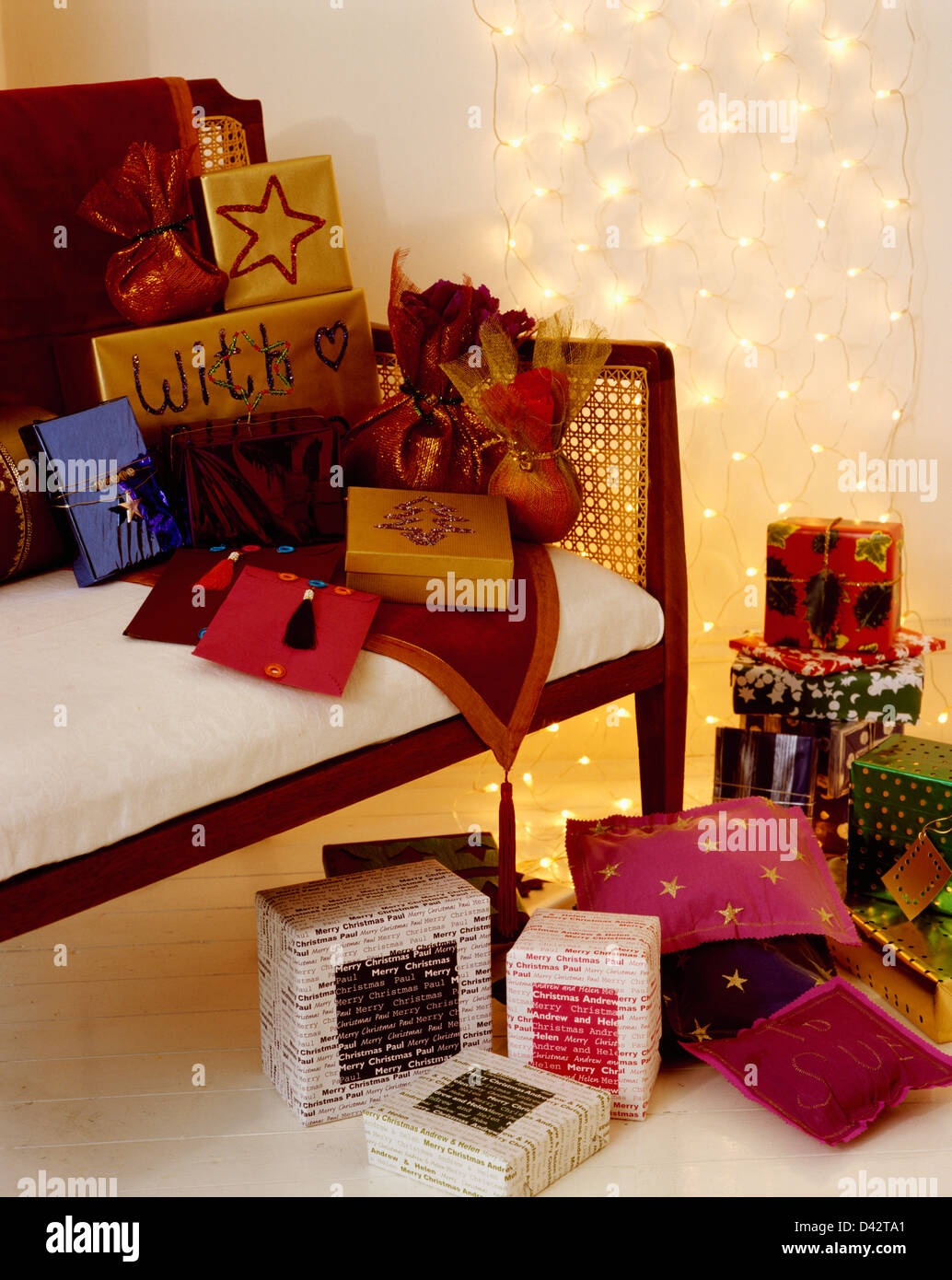 Colorfully gift-wrapped Christmas presents on sofa and floor beside net ...