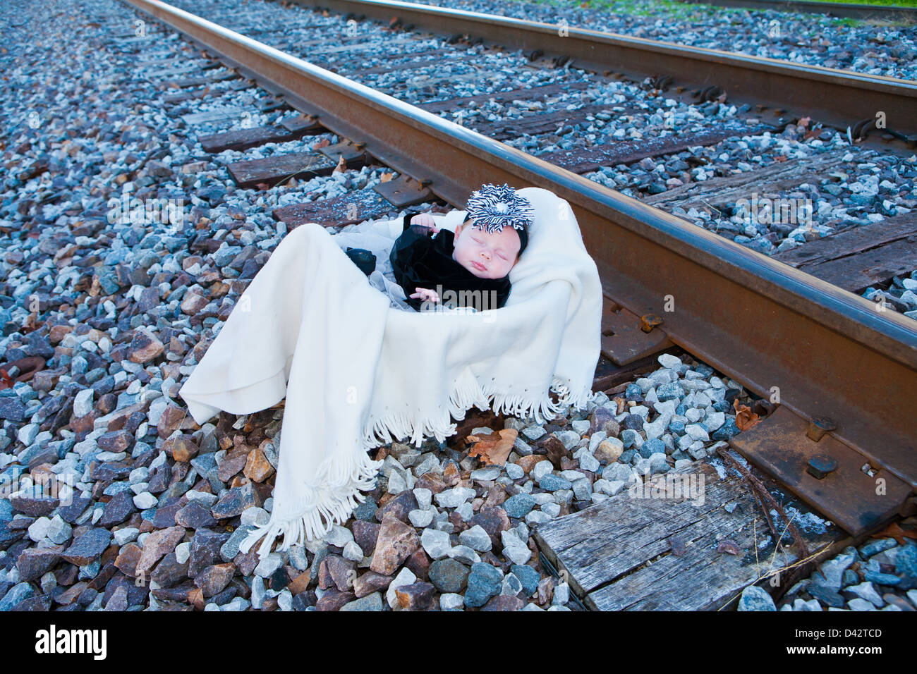 A small baby girl sleeping in a basket next to railroad tracks Stock ...