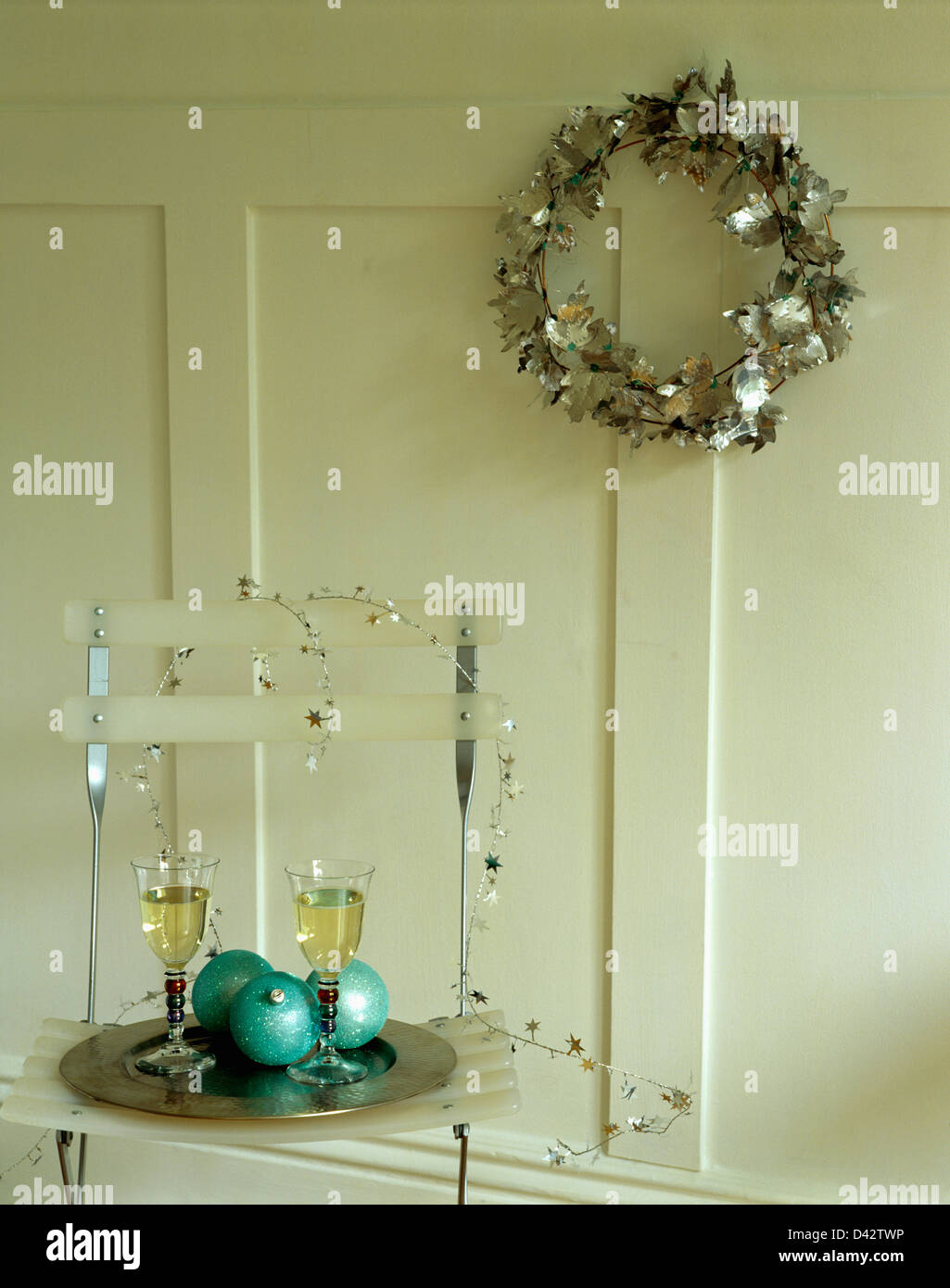 Punched tin foliage Christmas wreath on panelled wall above chair with ...